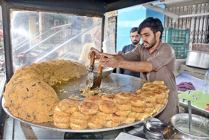 A shopkeeper preparing popular traditional food of Lahoris anda tikki ...