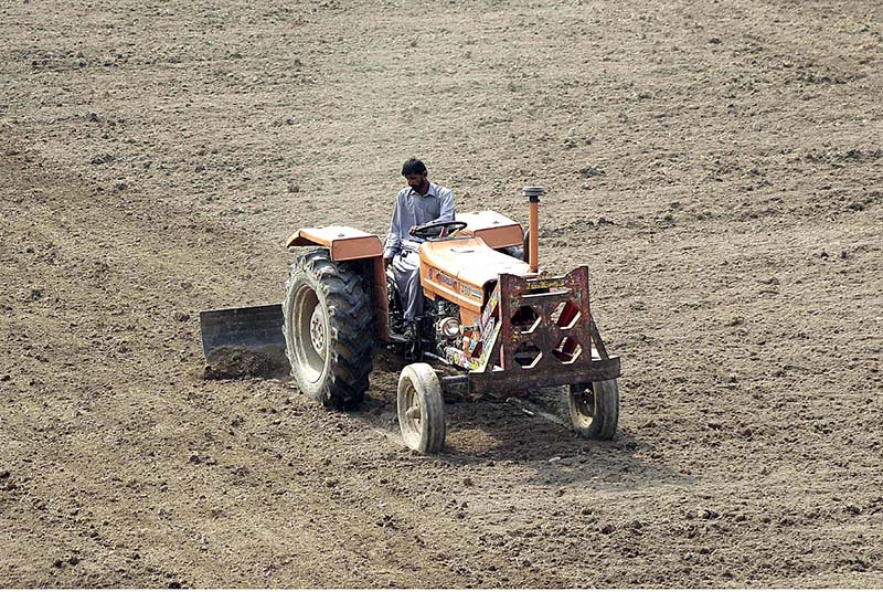 Farmer busy in leveling his farm field with the help of tractor for next crop