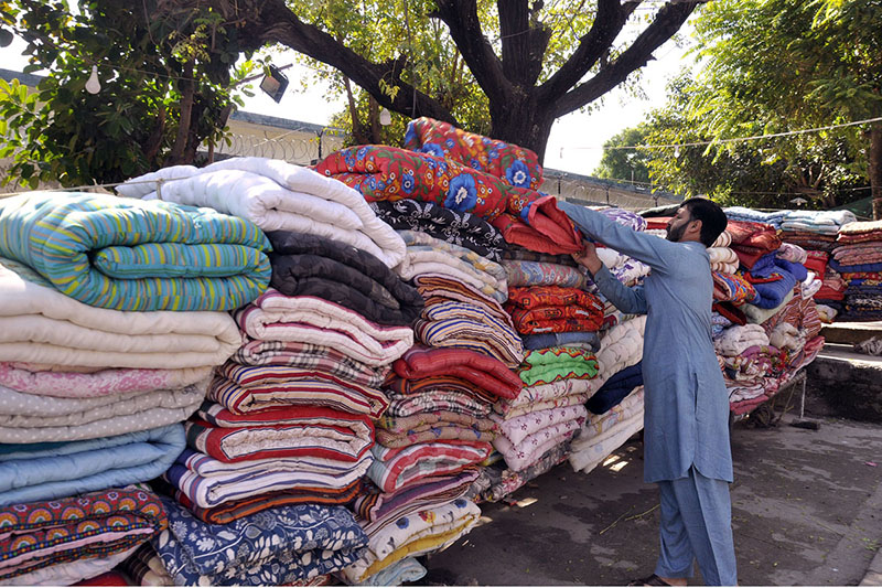 A man is sewing and manually making woven quilt at his work place for ...