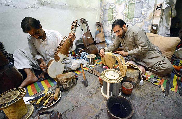 Workers busy in making traditional musical instrument (Rabab) at his ...