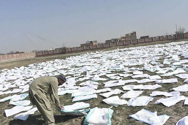 A worker drying washed plastic bags under the sun at his workplace