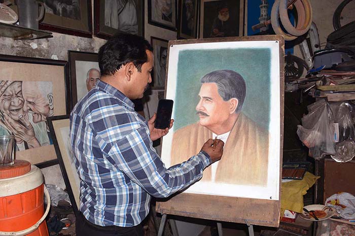 A painter giving final touch to portrait of Allama Muhammad Iqbal in ...