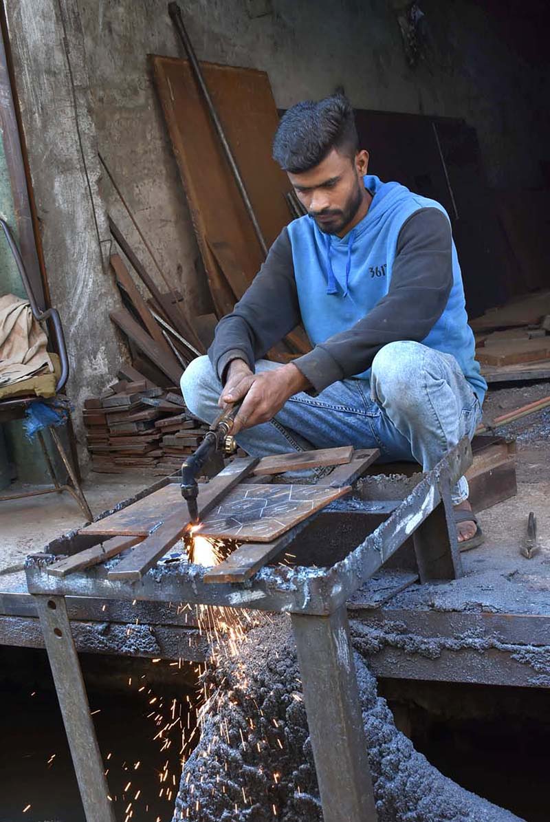 Skilled worker cutting thick iron sheet at his work place