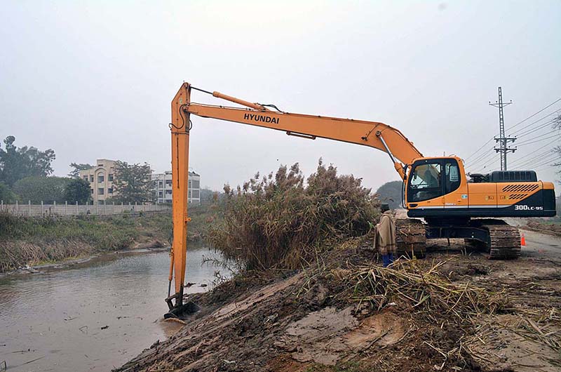 Irrigation department worker cleaning a canal with the help of ...
