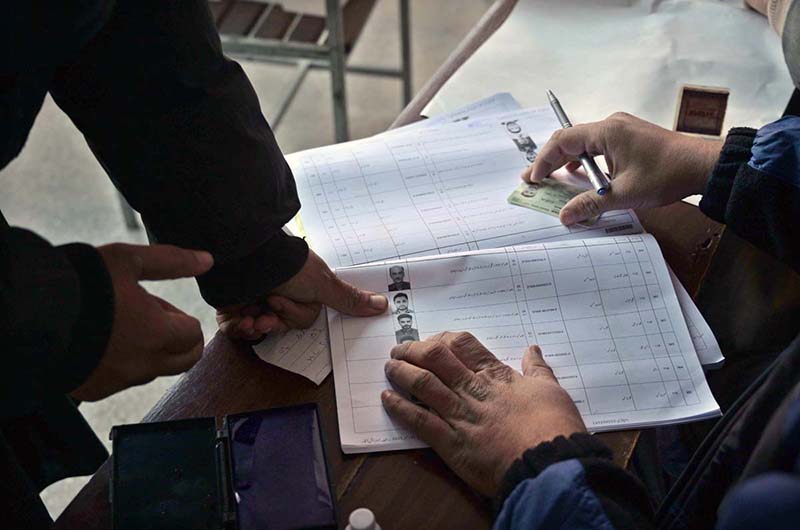 Polling Officers Searching The Name Of Voter In Voters List In The