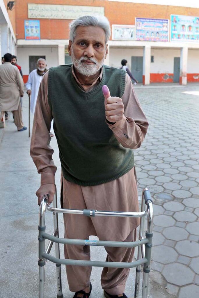 An elderly person shows his thumb after casting his vote at polling ...