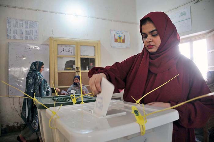 Polling officer marks the thumb of a woman voter before issuing ballot ...