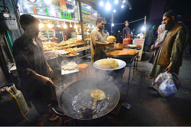 Vendor preparing traditional food item Tikkay for customers at Fawara ...