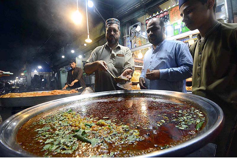 Vendor preparing traditional food item Tikkay for customers at Fawara ...