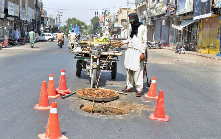 PTCL workers pulling the cable under the manhole with the help of the ...