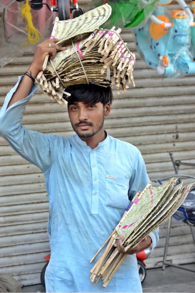 A vendor selling hand fans while shuttling on the road