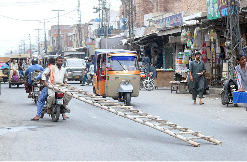 A person holding a ladder while sitting on the rear seat of a ...