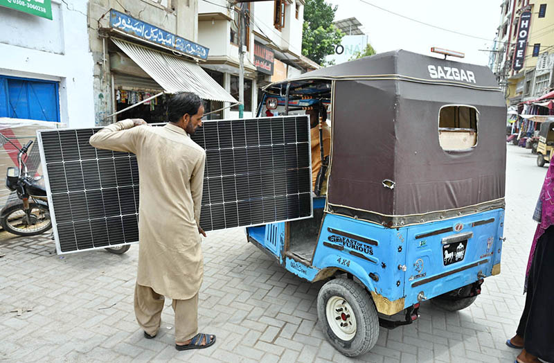 A worker loads a solar panel onto a rickshaw at Bacha Khan Chowk ...