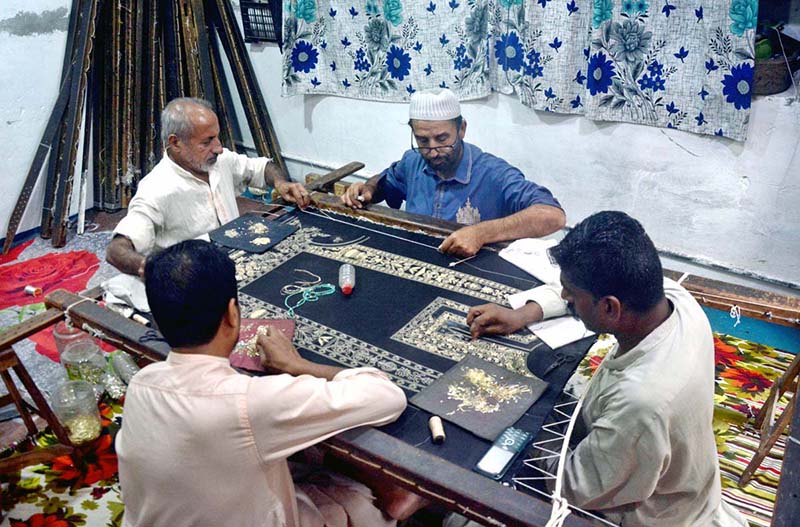 Workers are busy embroidery work on fancy clothes at their workplace.