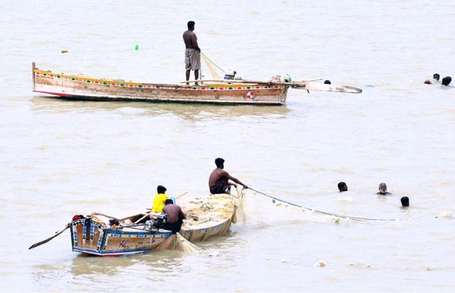 Fishermen busy in catching fish with fishing net on the boat at Indus ...