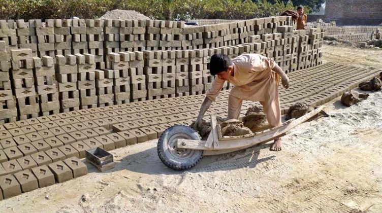 Workers unload clay to make bricks for construction industries at a ...